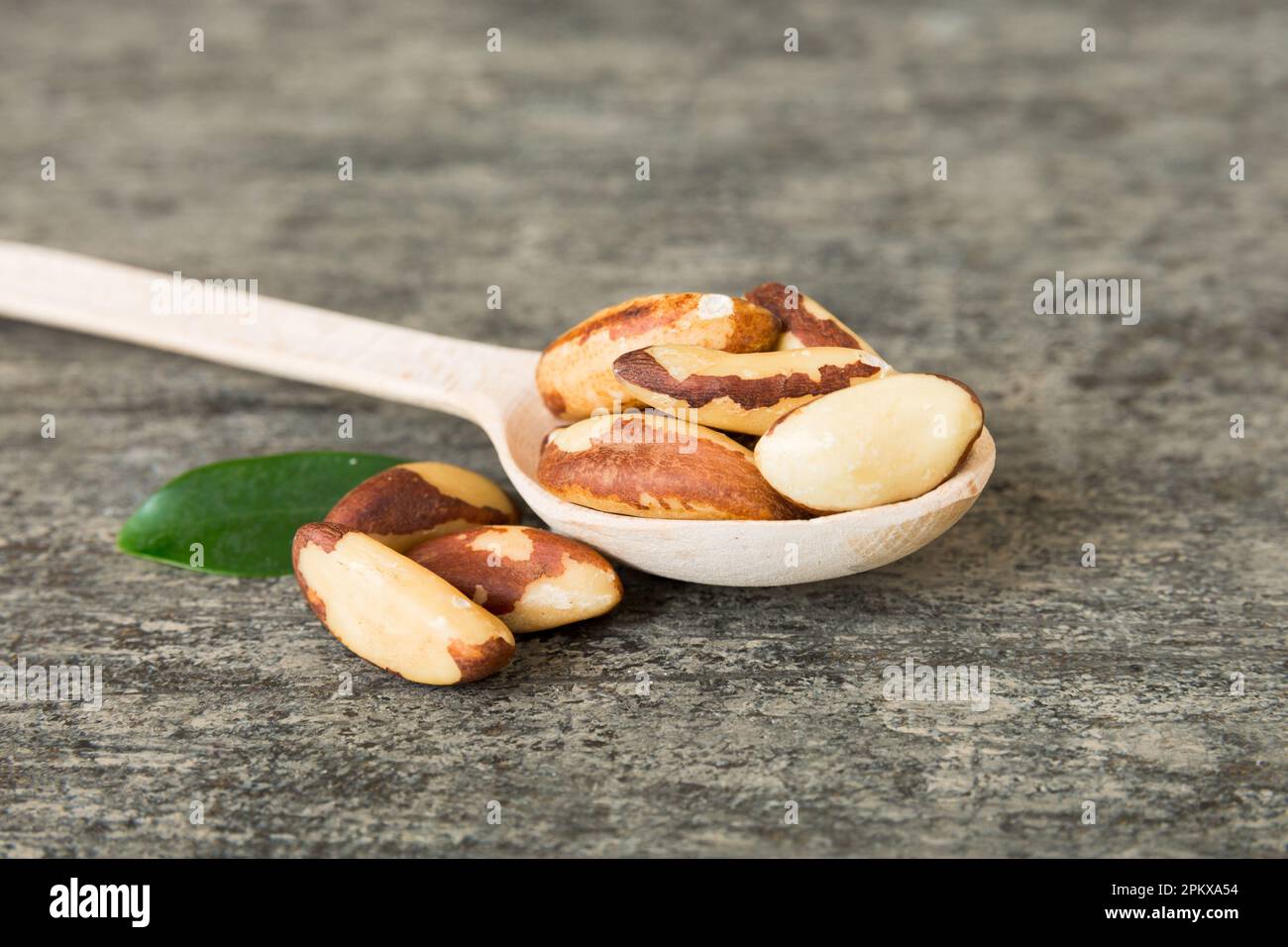 Fresh healthy brazil nuts in spoon on colored table background. Top ...