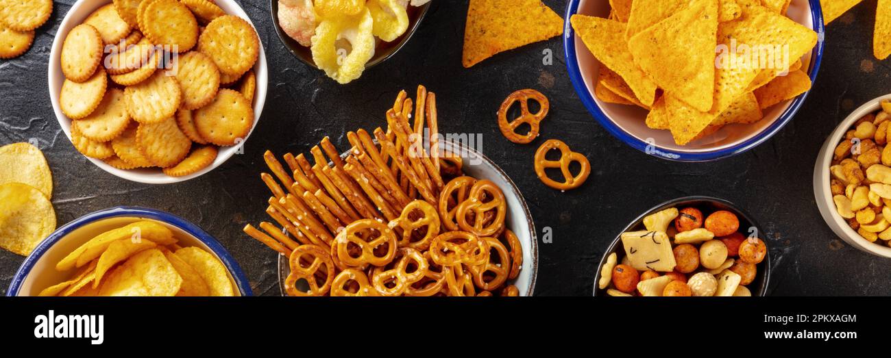 Salty snacks, party mix panorama. A variety of crispy appetizers ...