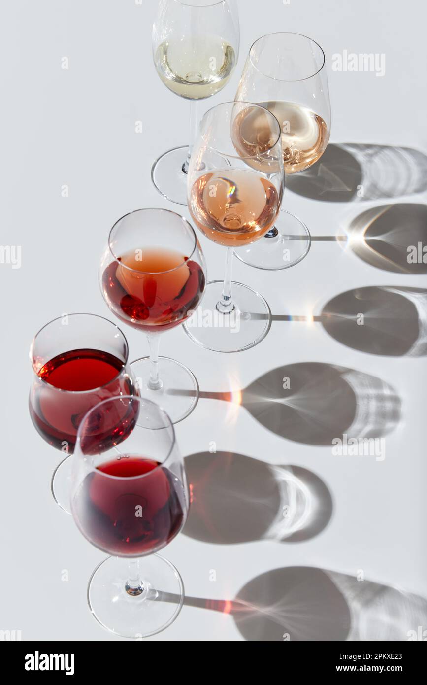 Vertical image of wine glasses standing in a line against white ...