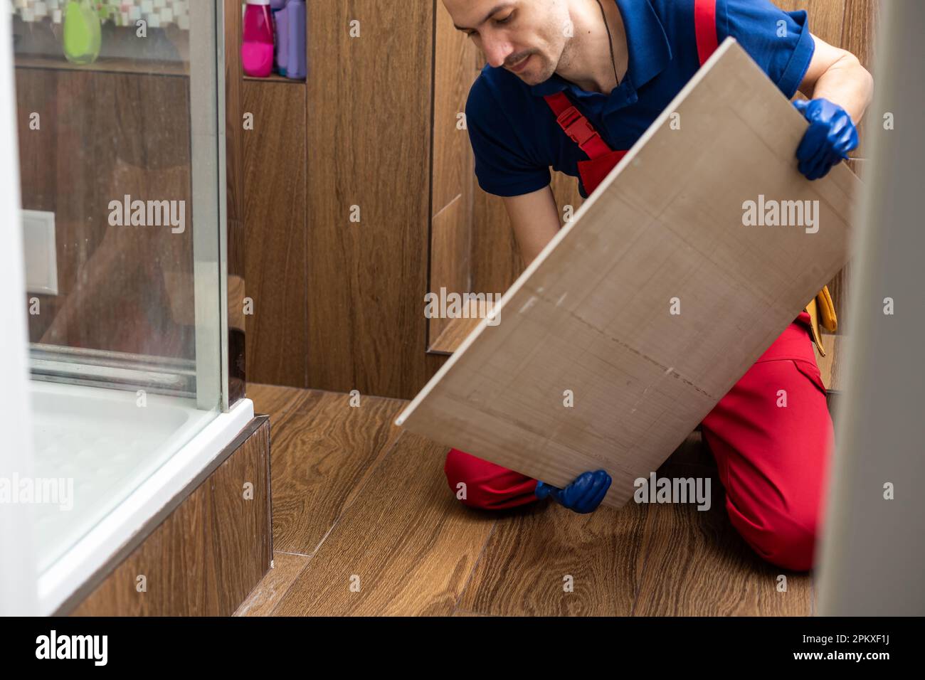 Construction worker wearing bib overalls and hard hat cutting ceramic ...