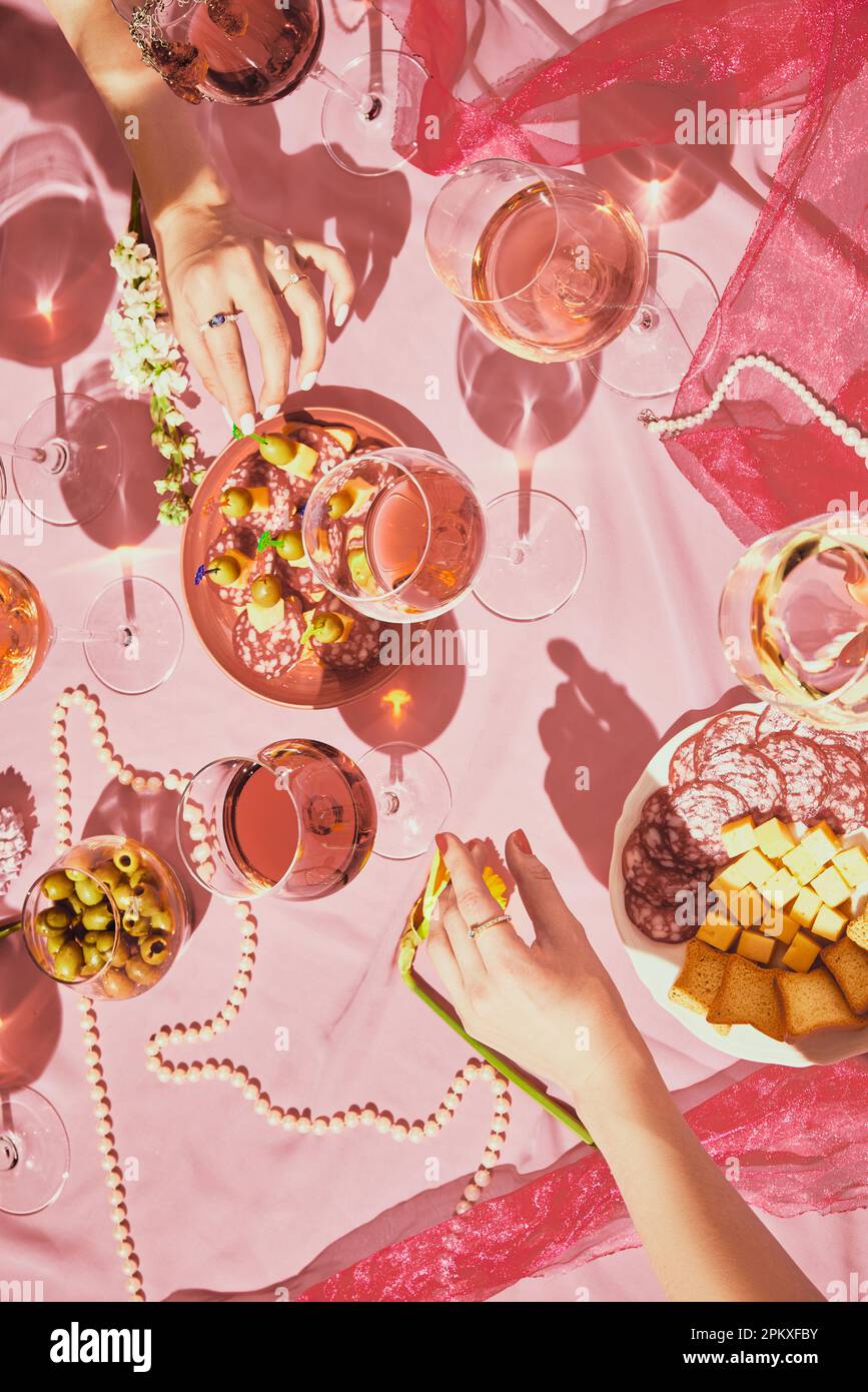 Vertical image of female hands over table with rose wine and appetizers ...