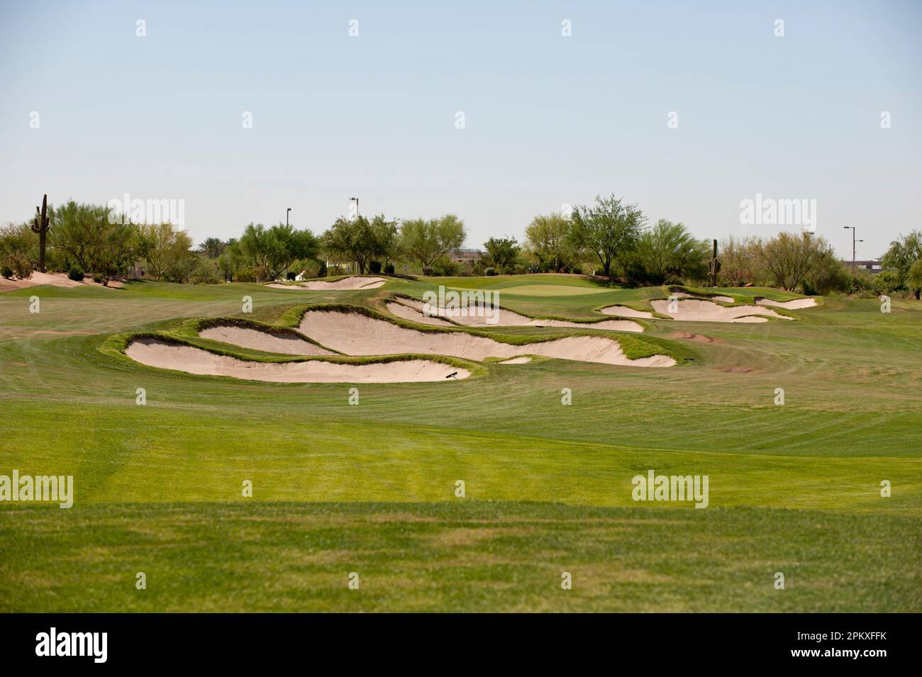A scenic landscape featuring a lush green golf course with sand bunkers ...