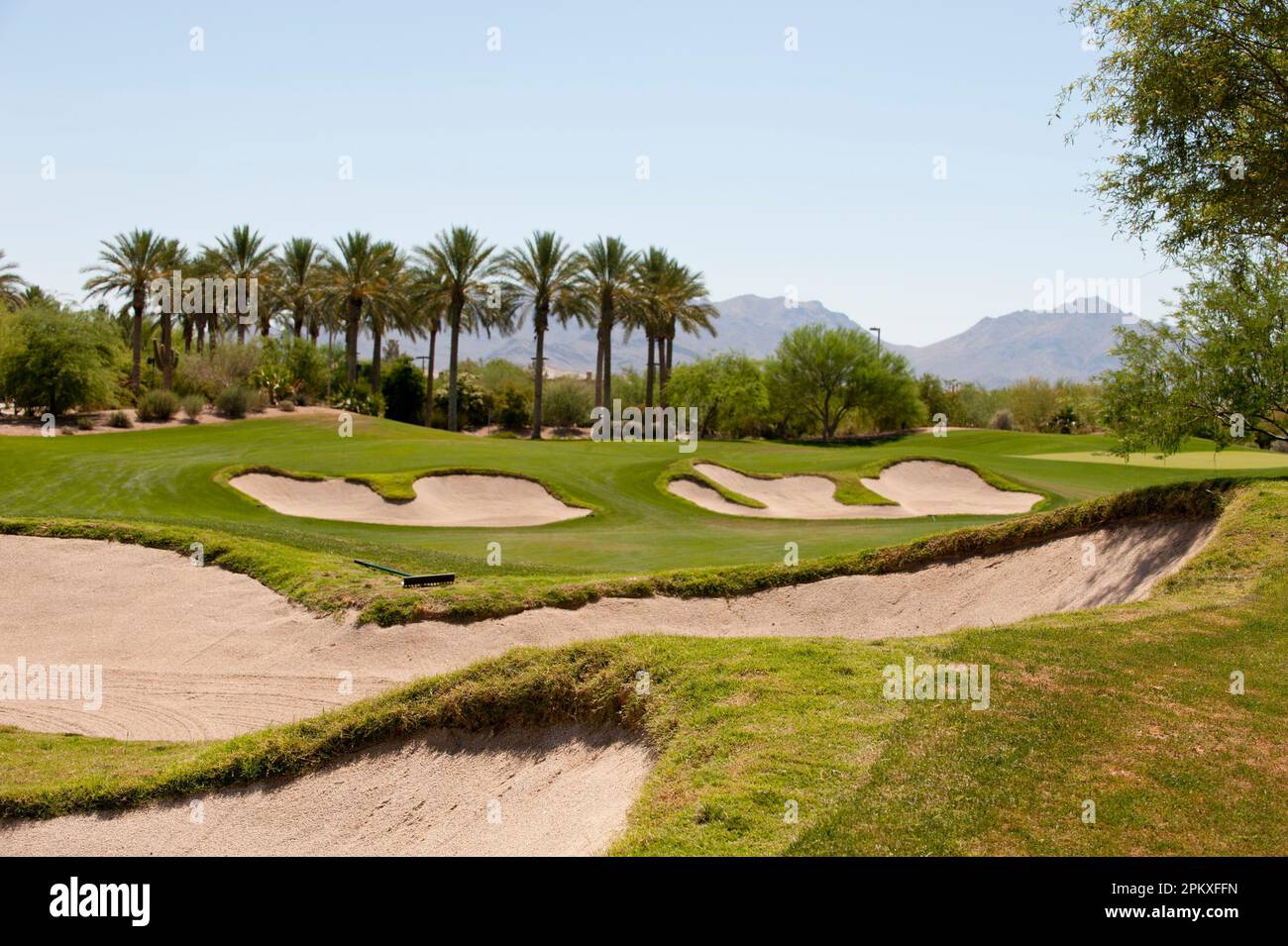A scenic landscape featuring a lush green golf course with sand bunkers ...