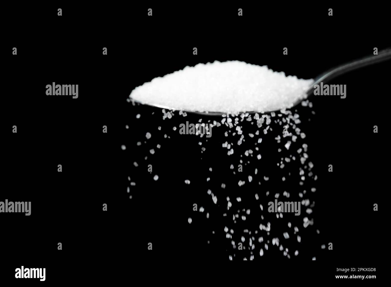 Macro photography of a teaspoon with white sugar on a black background ...
