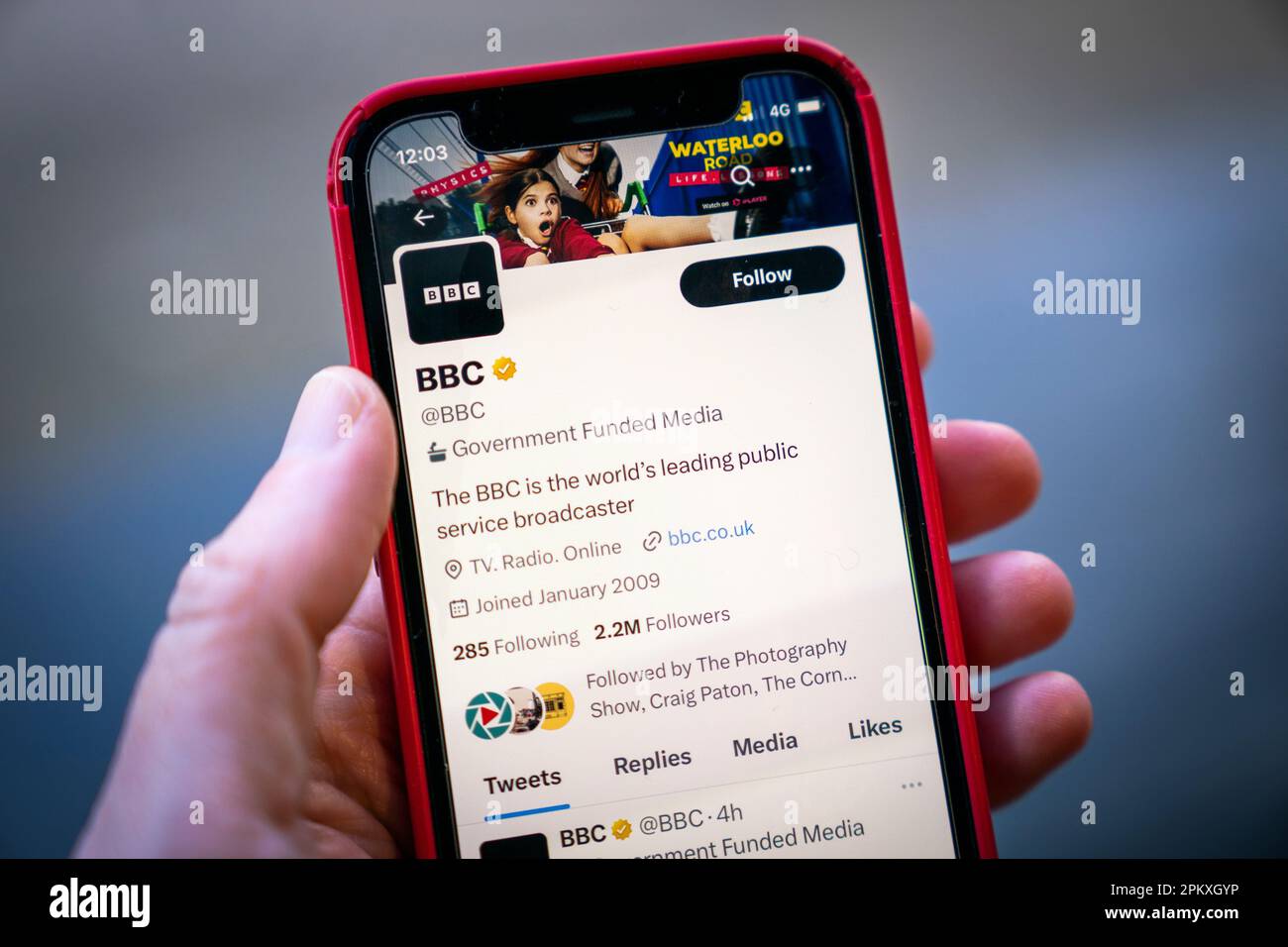 A person holds a smart phone showing the Twitter account for the BBC ...