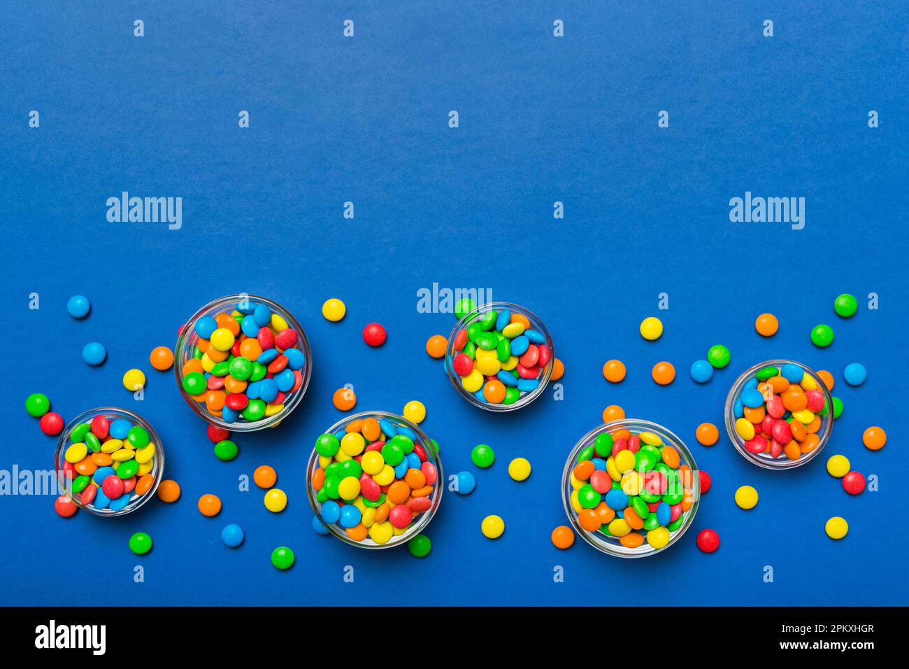 different colored round candy in bowl and jars. Top view of large ...
