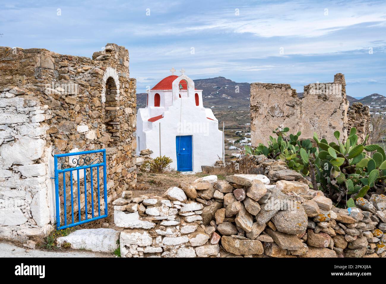 Entrance gate with ruined wall, small Cycladic white and red Orthodox ...