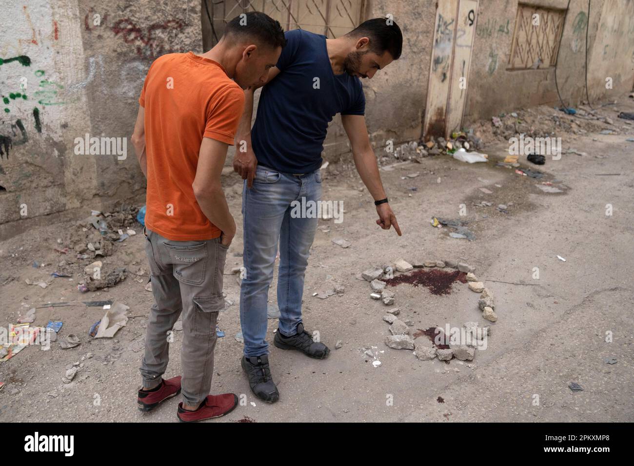 Palestinians show a blood stain on the ground, at the site of the ...