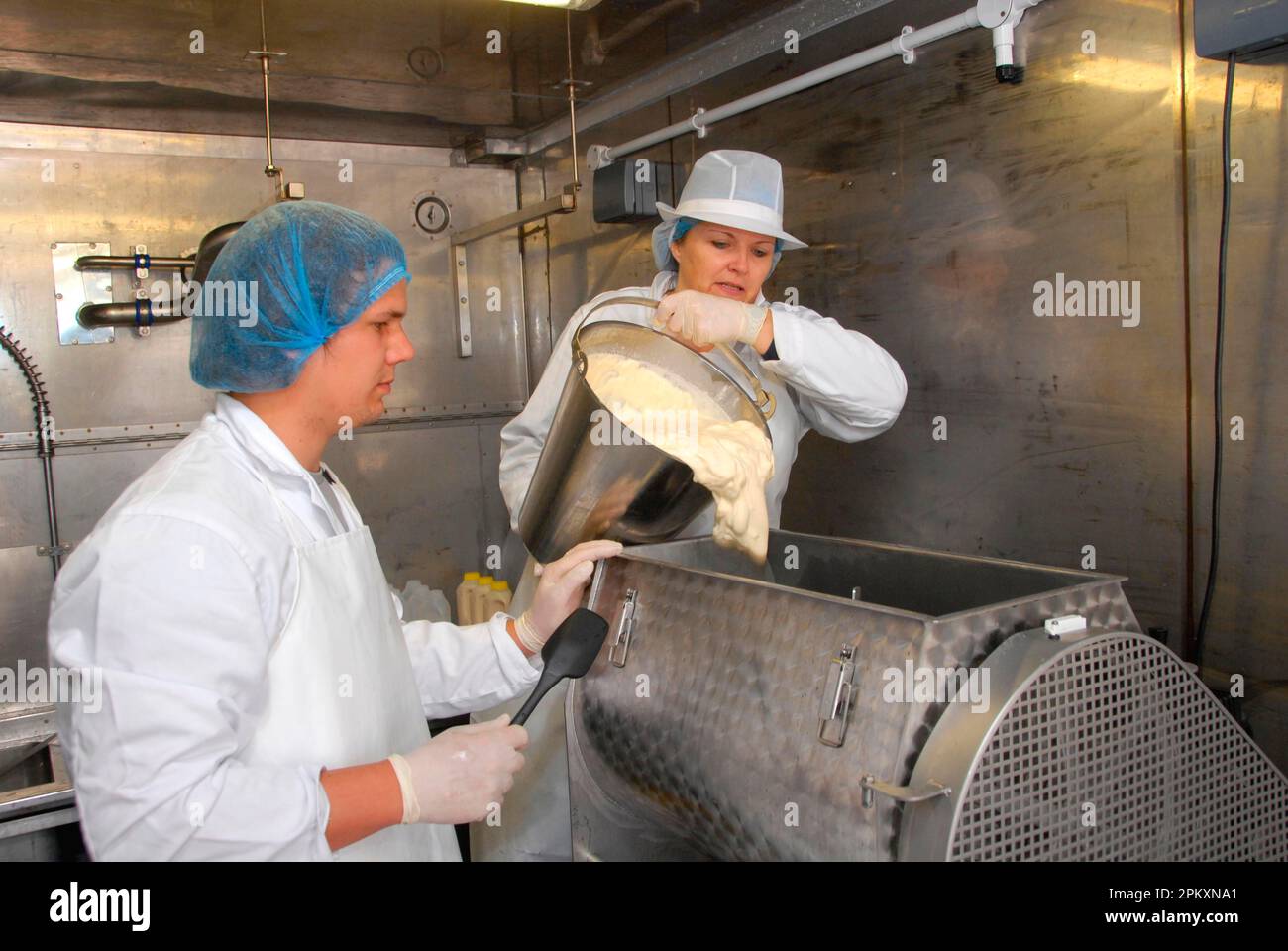 Workers pour raw, unpasteurised cream into a churn and make organic ...