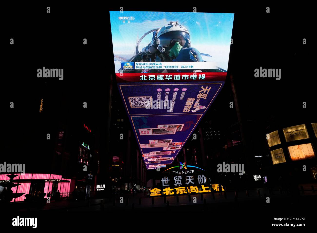 An outdoor screen depicts a Chinese fighter jet pilot giving a thumbs ...