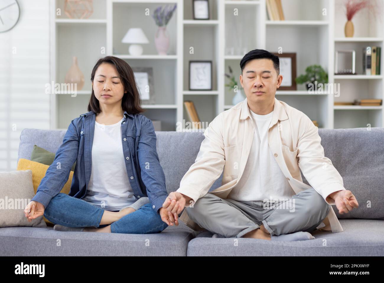 Happy asian family at home on sofa meditating, couple man and woman ...