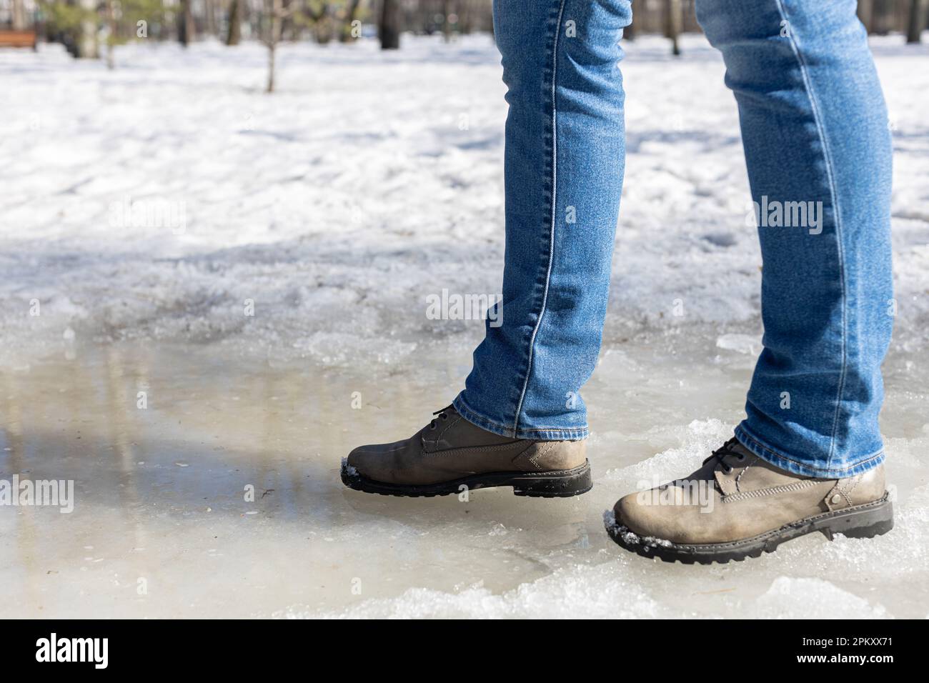 man walking on ice in the park. a man walks through a puddle in winter ...