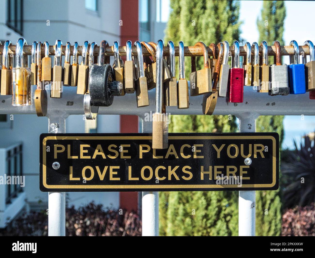 A steel gate adorned with multiple love locks and a cautionary sign ...