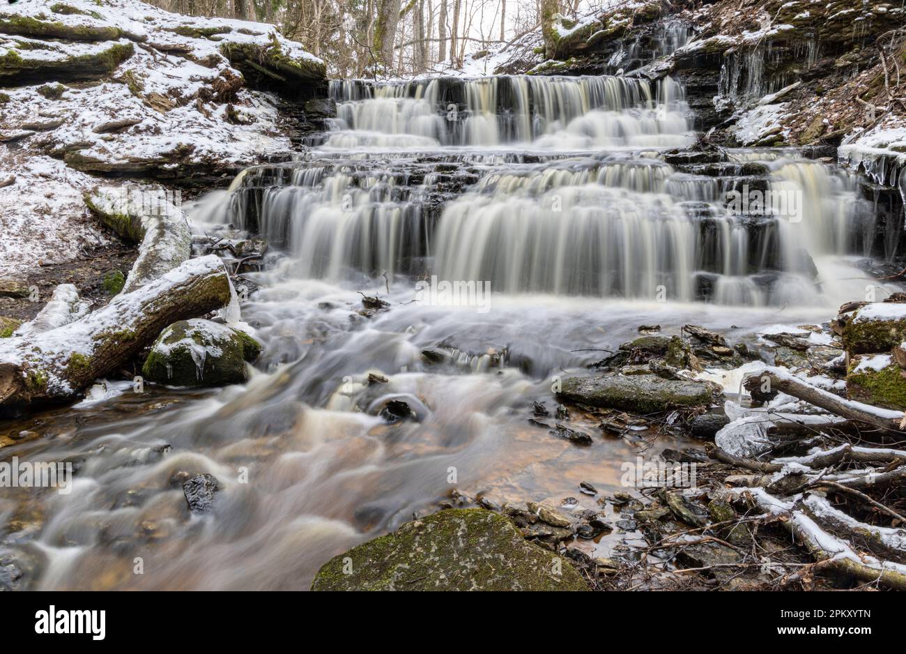 This striking winter scene features a majestic waterfall surrounded by ...