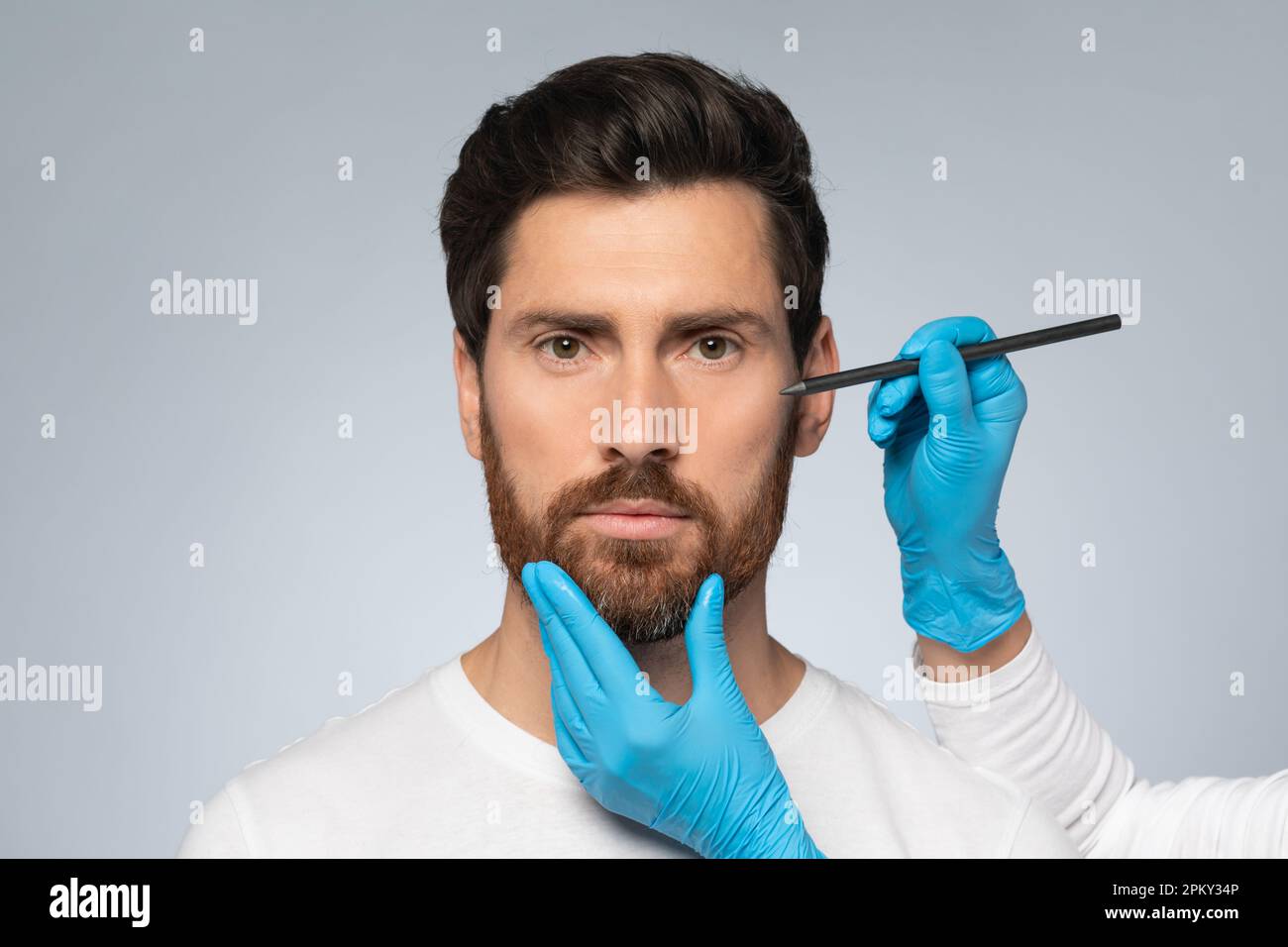 Middle aged man getting marks on face for cosmetic surgery, plastic ...