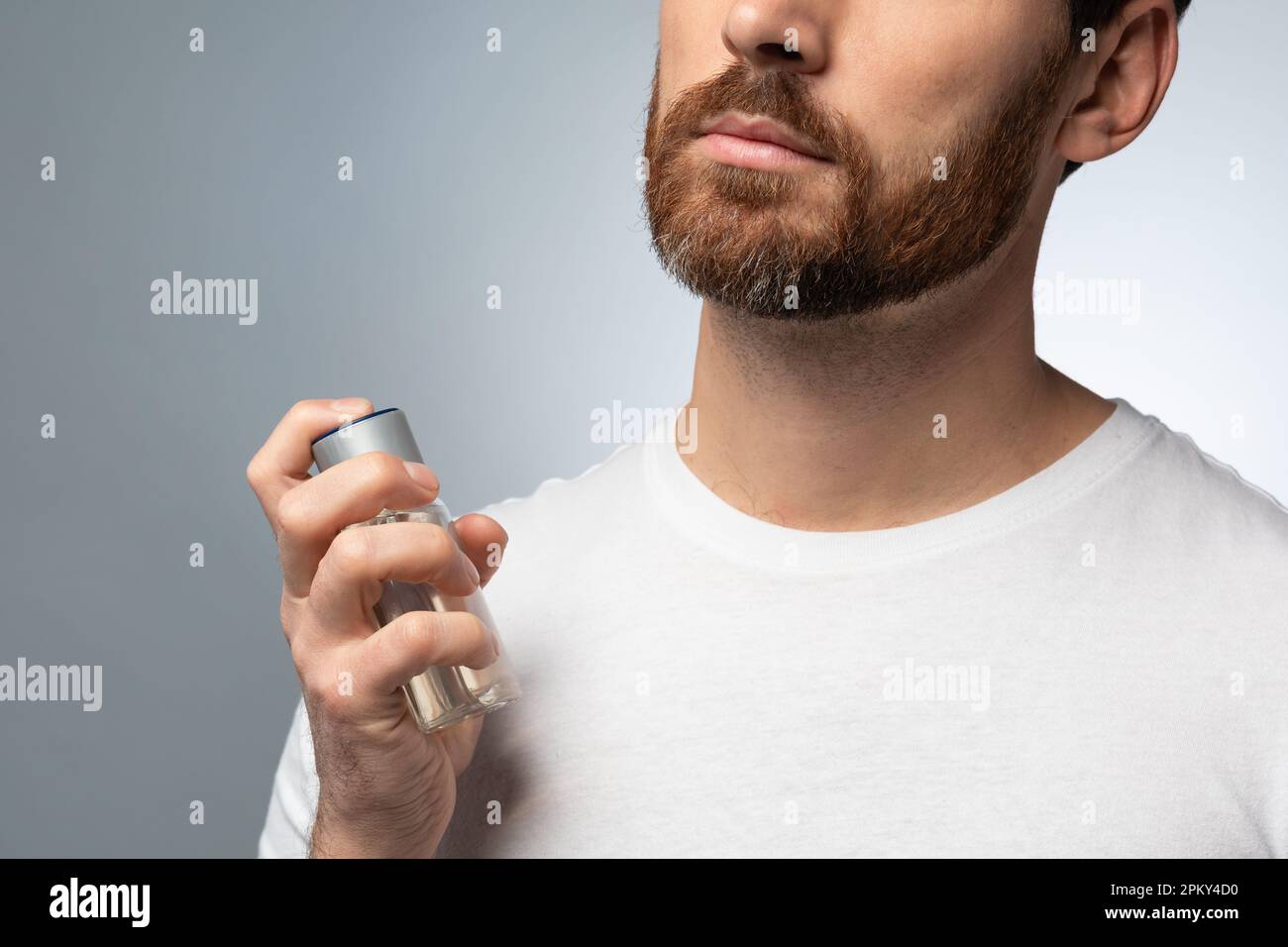 Unrecognizable bearded man spraying perfume on himself, using cologne ...