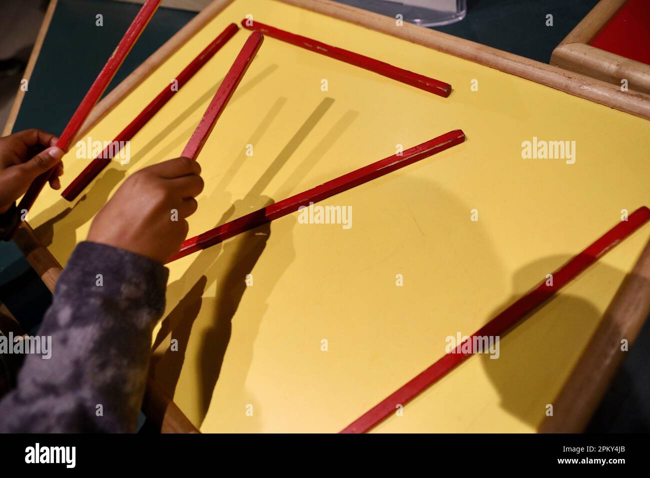 A young child playing with red long sticks, enjoying their time ...