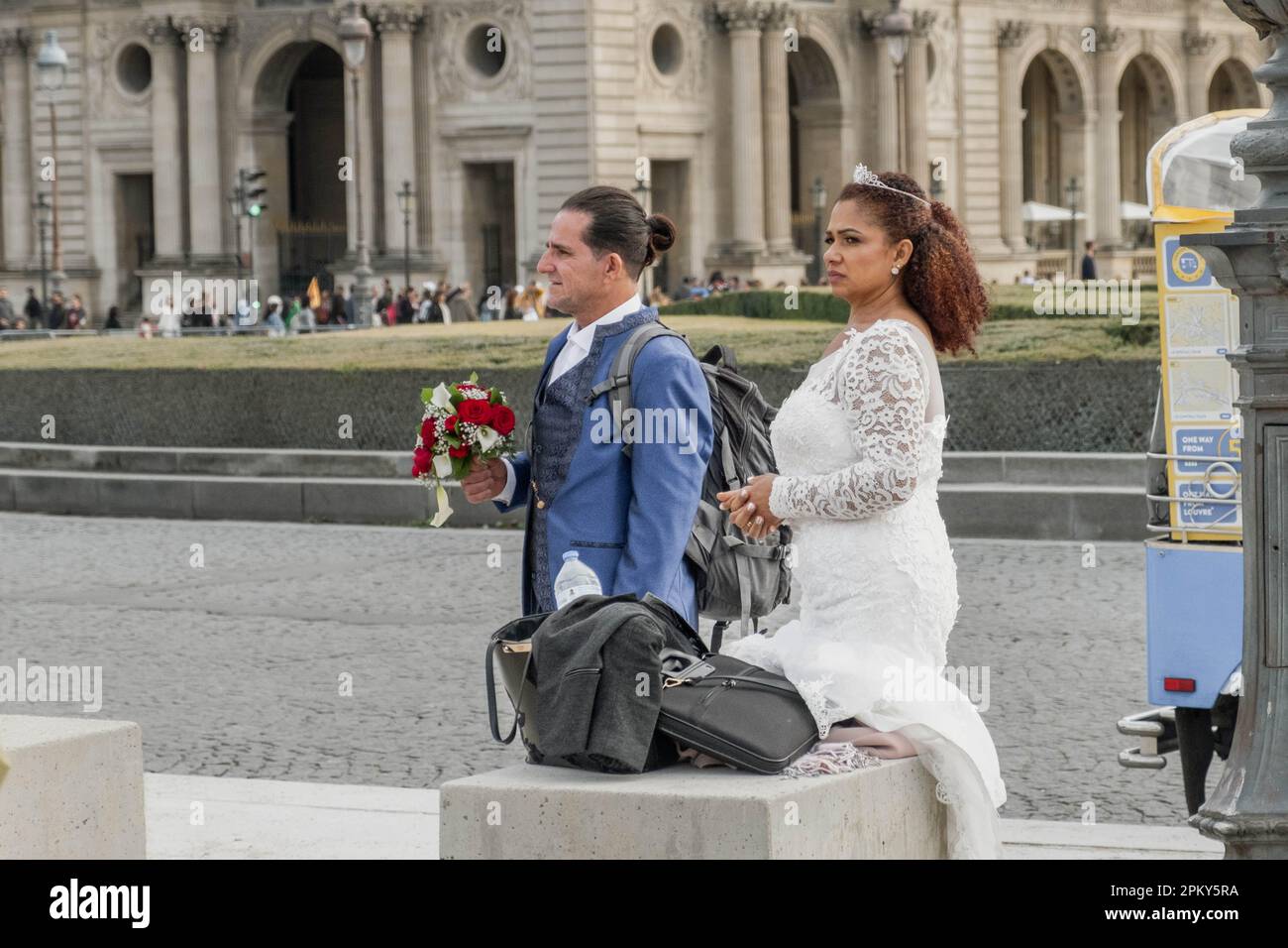 A romantic couple in wedding attire posing near the Louvre Museum in ...