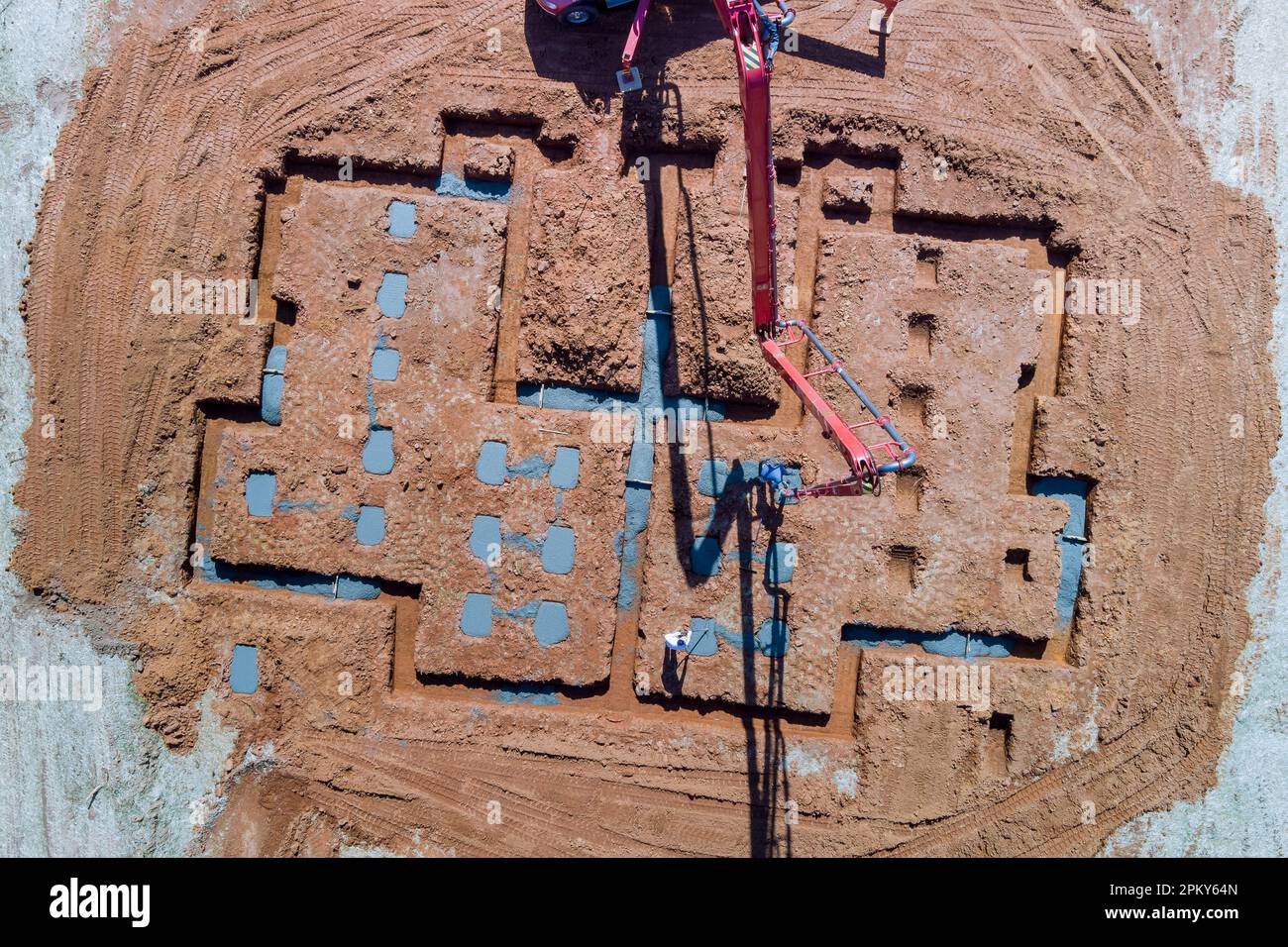Worker pouring concrete into foundation of house using concrete pump ...