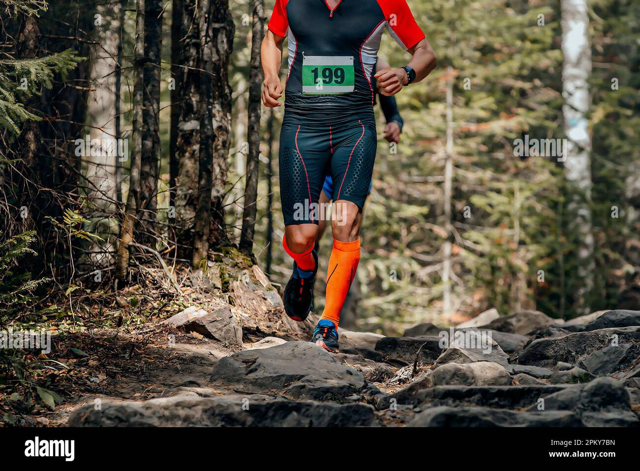 male runner in compression socks running forest trail over stones ...
