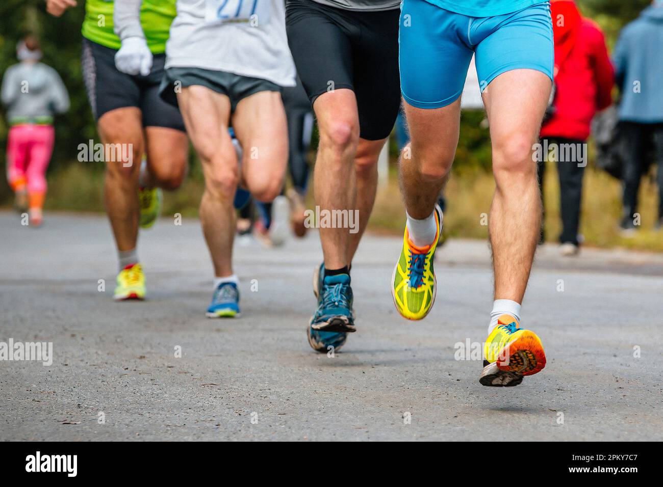 close-up legs group athletes runners running race on road, men jogging ...