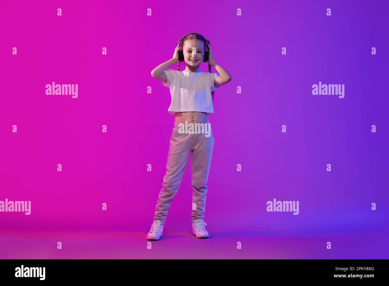 Sweet preteen child girl in summer outfit using wireless headphones ...