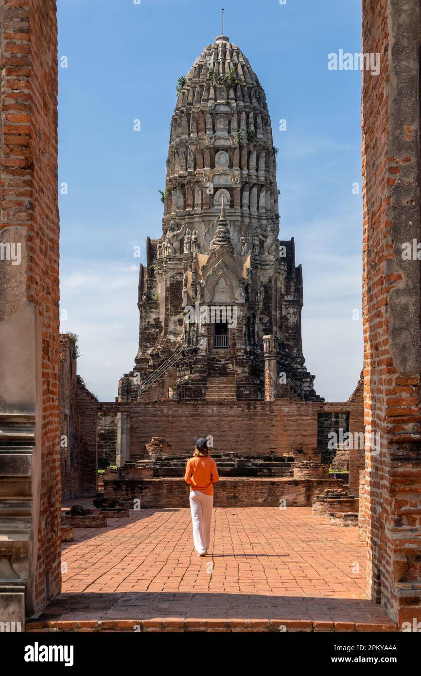 A woman in a white shirt and blue jeans stands in awe of the ancient ...