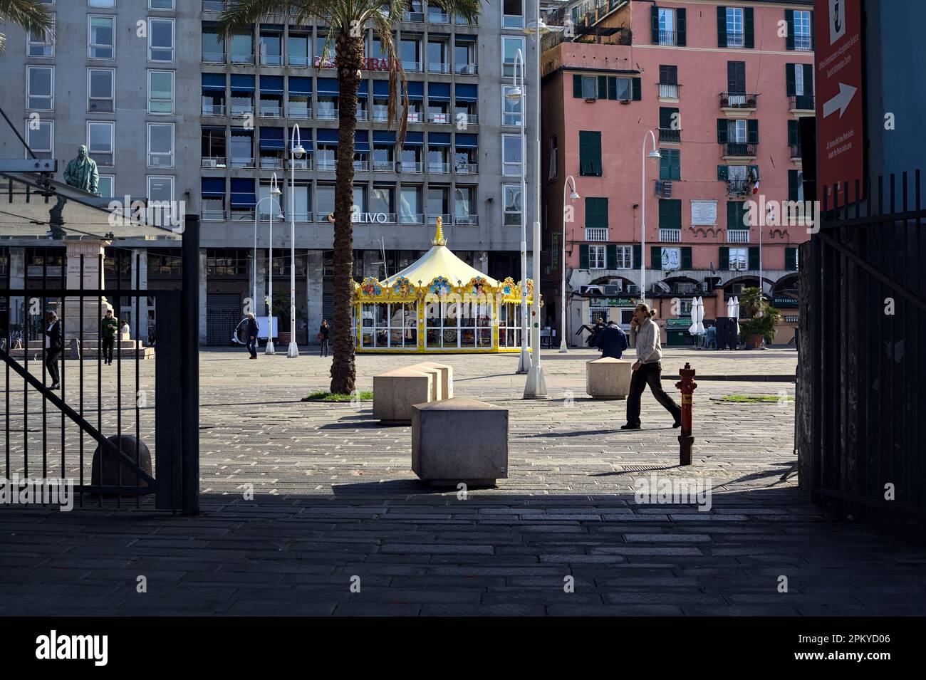 Small yellow carousel in a square among buildings framed by a porch ...