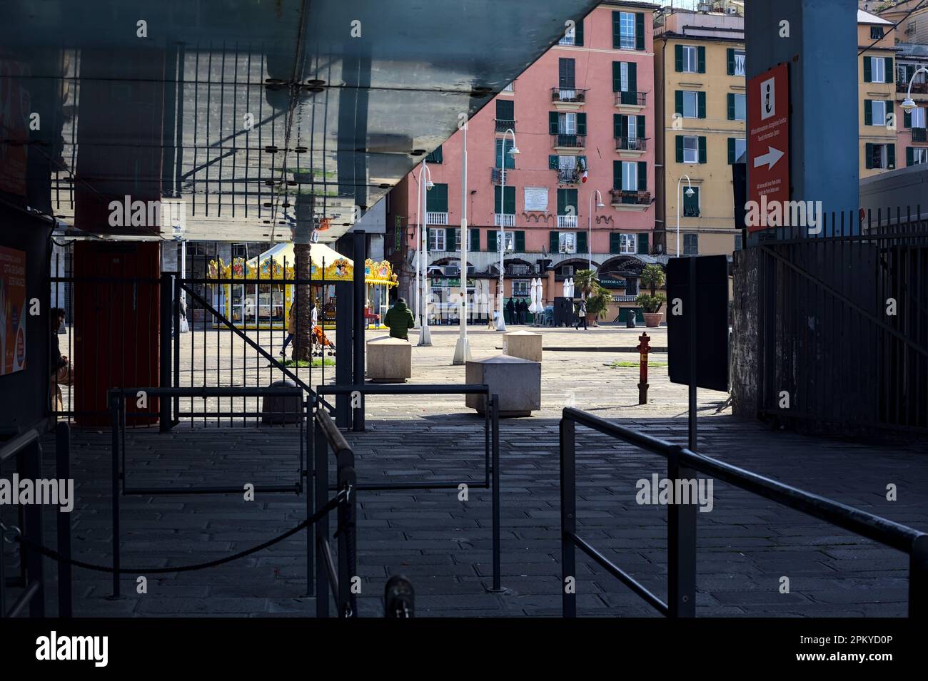 Small yellow carousel in a square among buildings framed by a porch ...