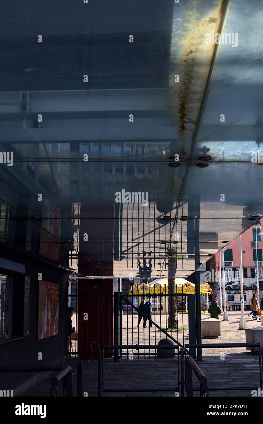 Small yellow carousel in a square among buildings framed by a porch ...