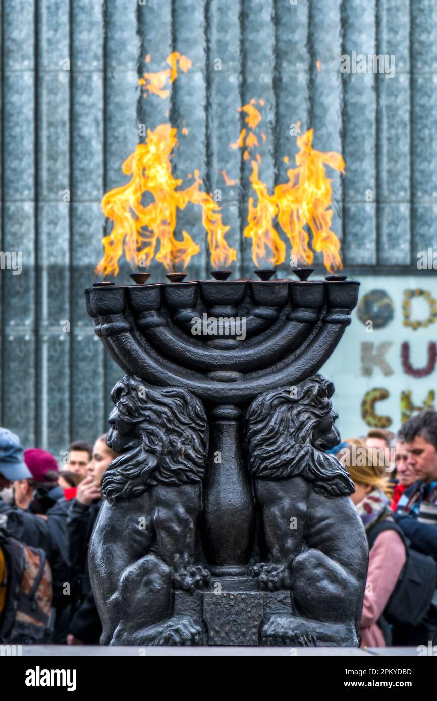 Menorah with burning flame in front of the Warsaw Ghetto Heroes ...
