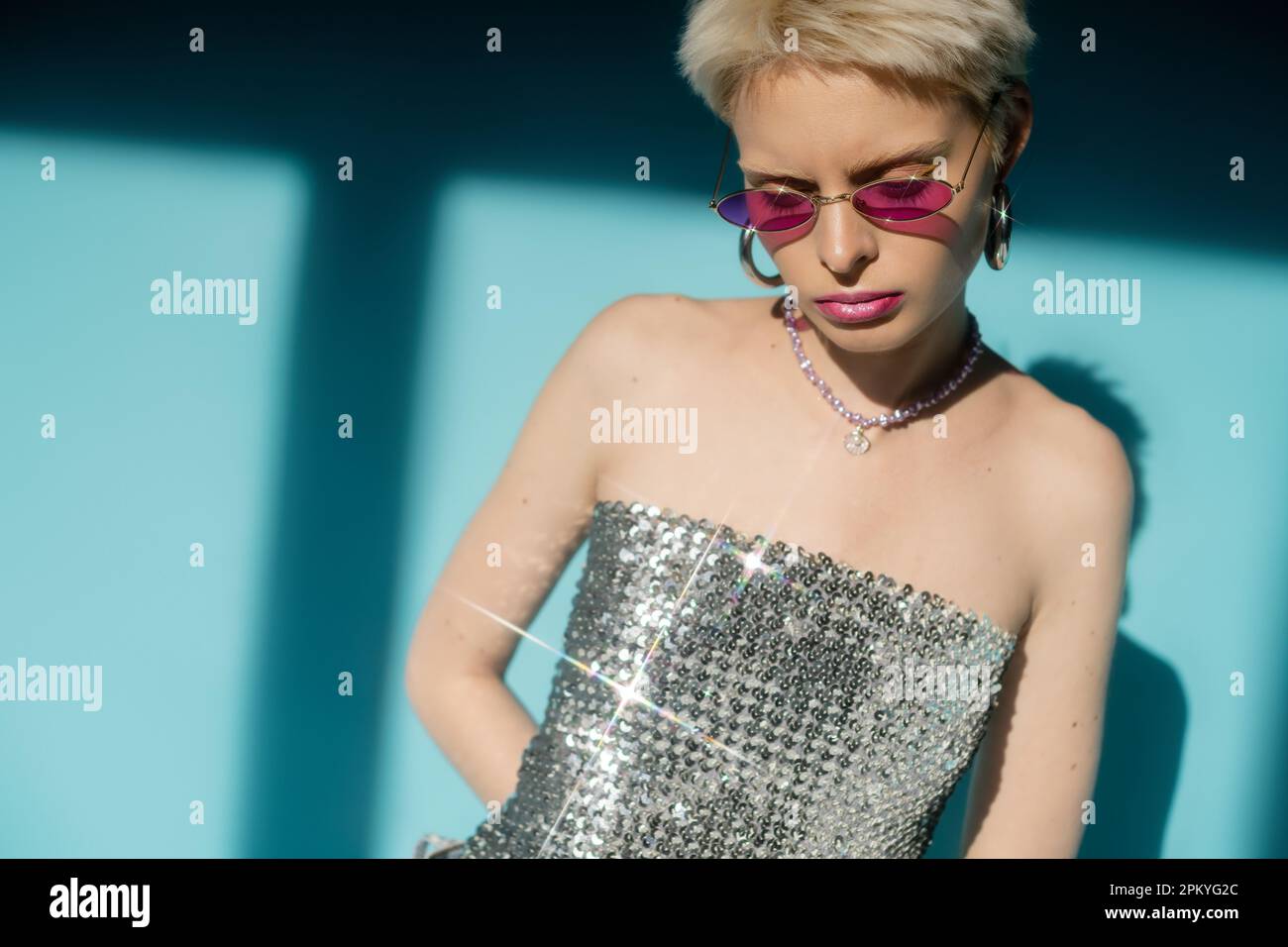 sunlight on body of albino model in pink sunglasses and shiny top with ...