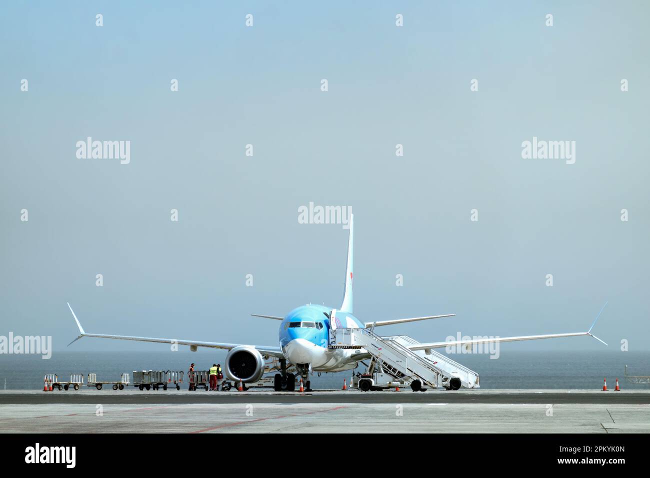 A TUI aircraft on the apron of a busy airport . Servicing Teams are ...