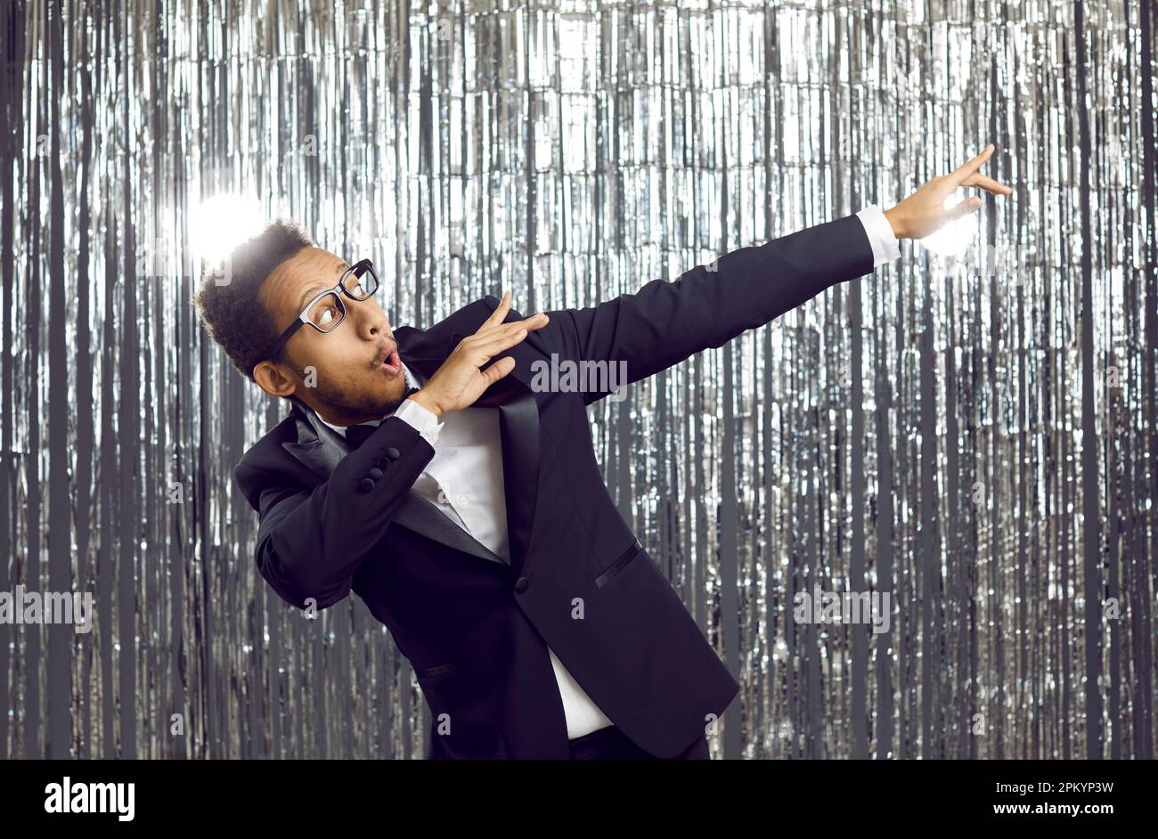 Happy funny young ethnic guy in trendy tuxedo dab dancing and having ...