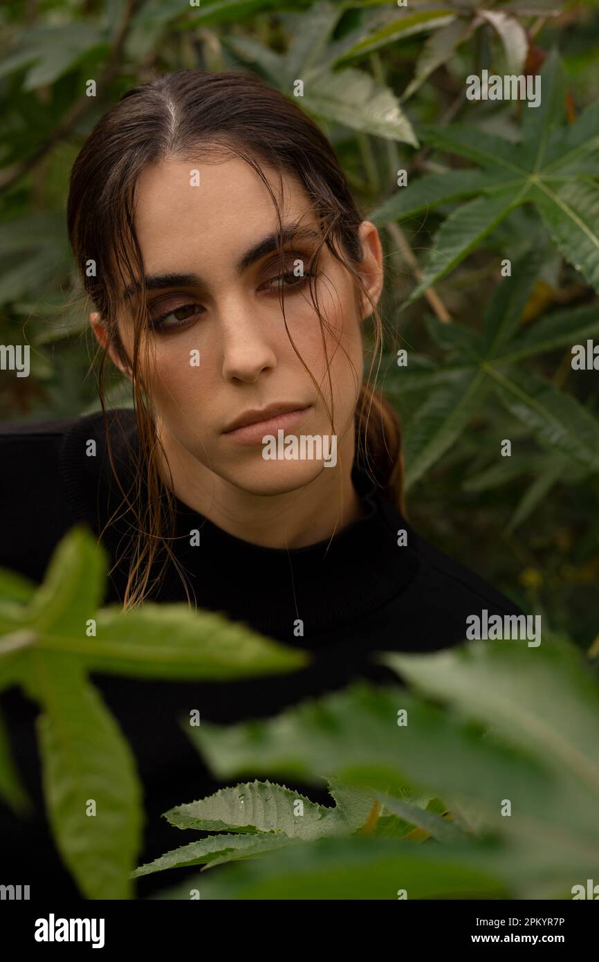 Calm young female model in black outfit with makeup standing looking ...