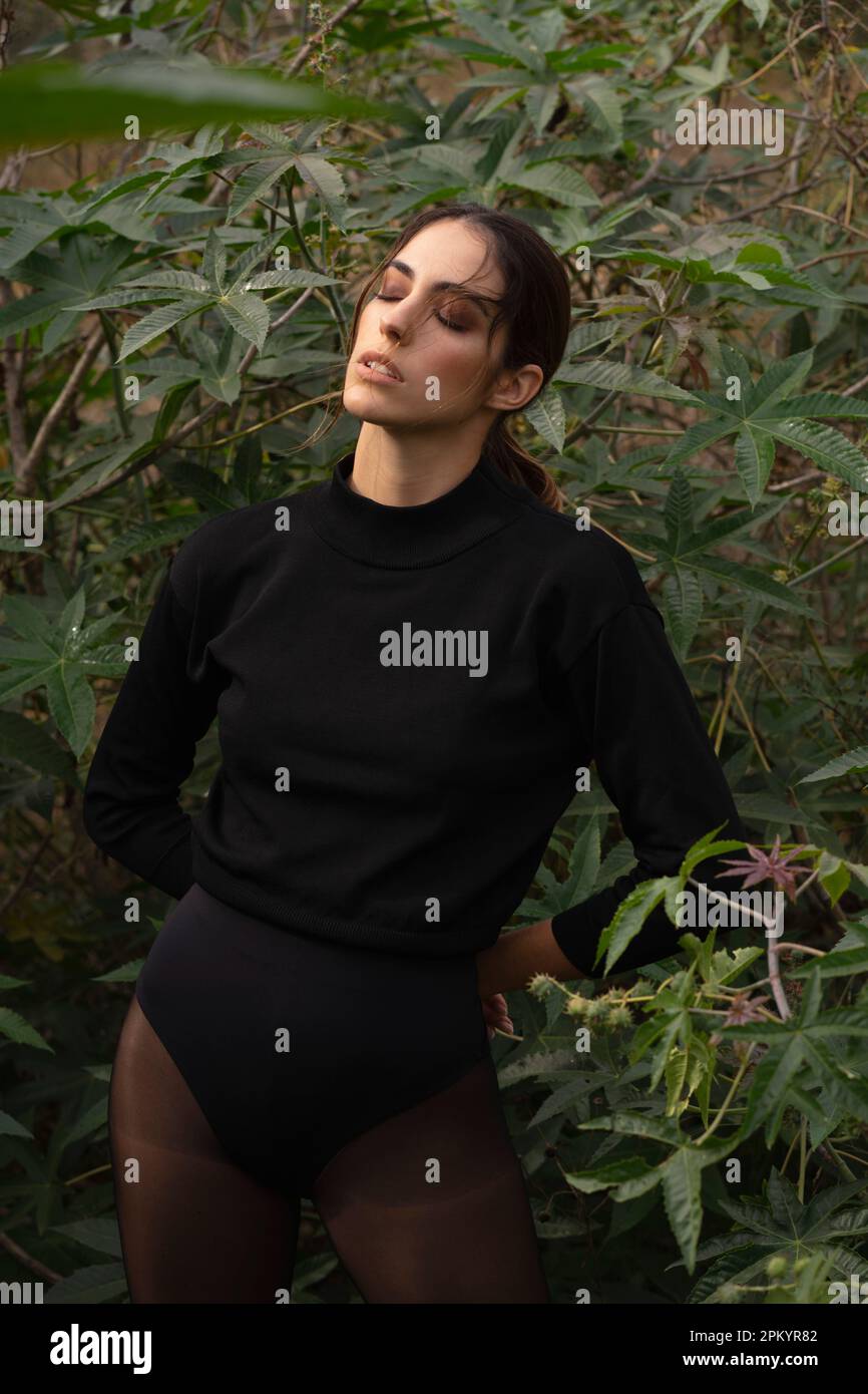 Calm young female model in black outfit with makeup and closed eyes ...