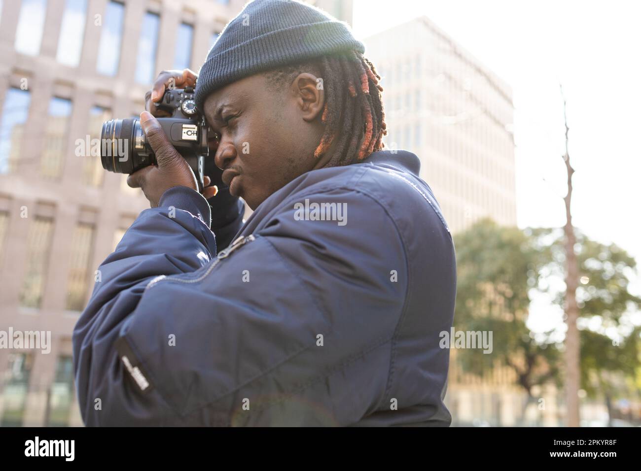 Black male photographer with professional photo camera standing against ...