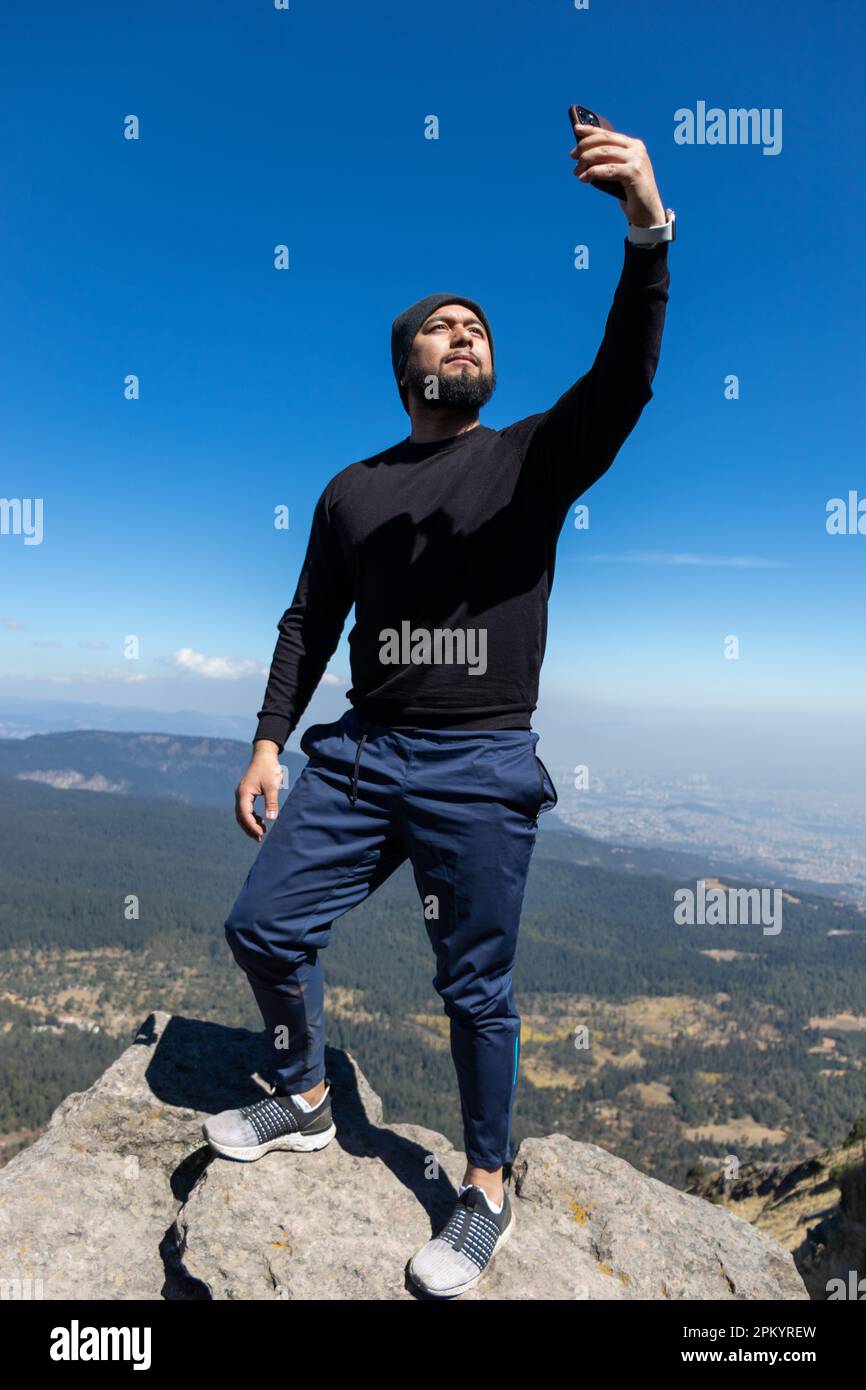 Full body of confident male hiker in casual clothes standing on peak of ...
