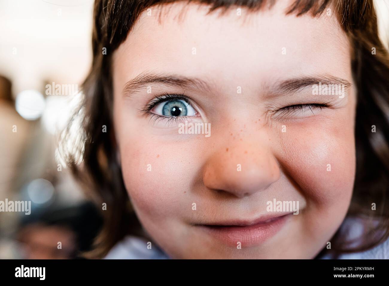 Portrait of funny preschool girl with freckles and blue eyes winking at ...