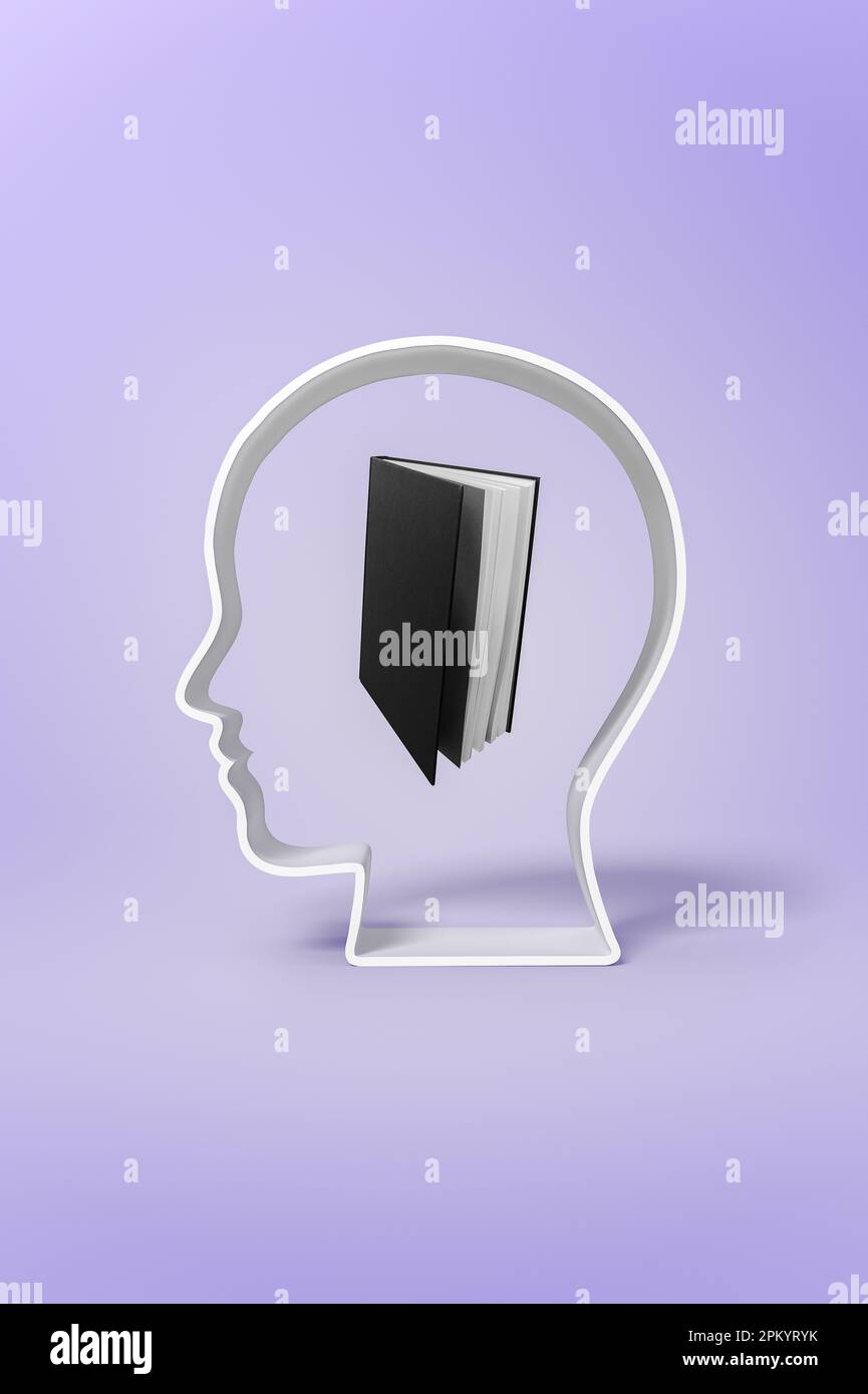 Black book with half open pages placed inside human head against purple ...