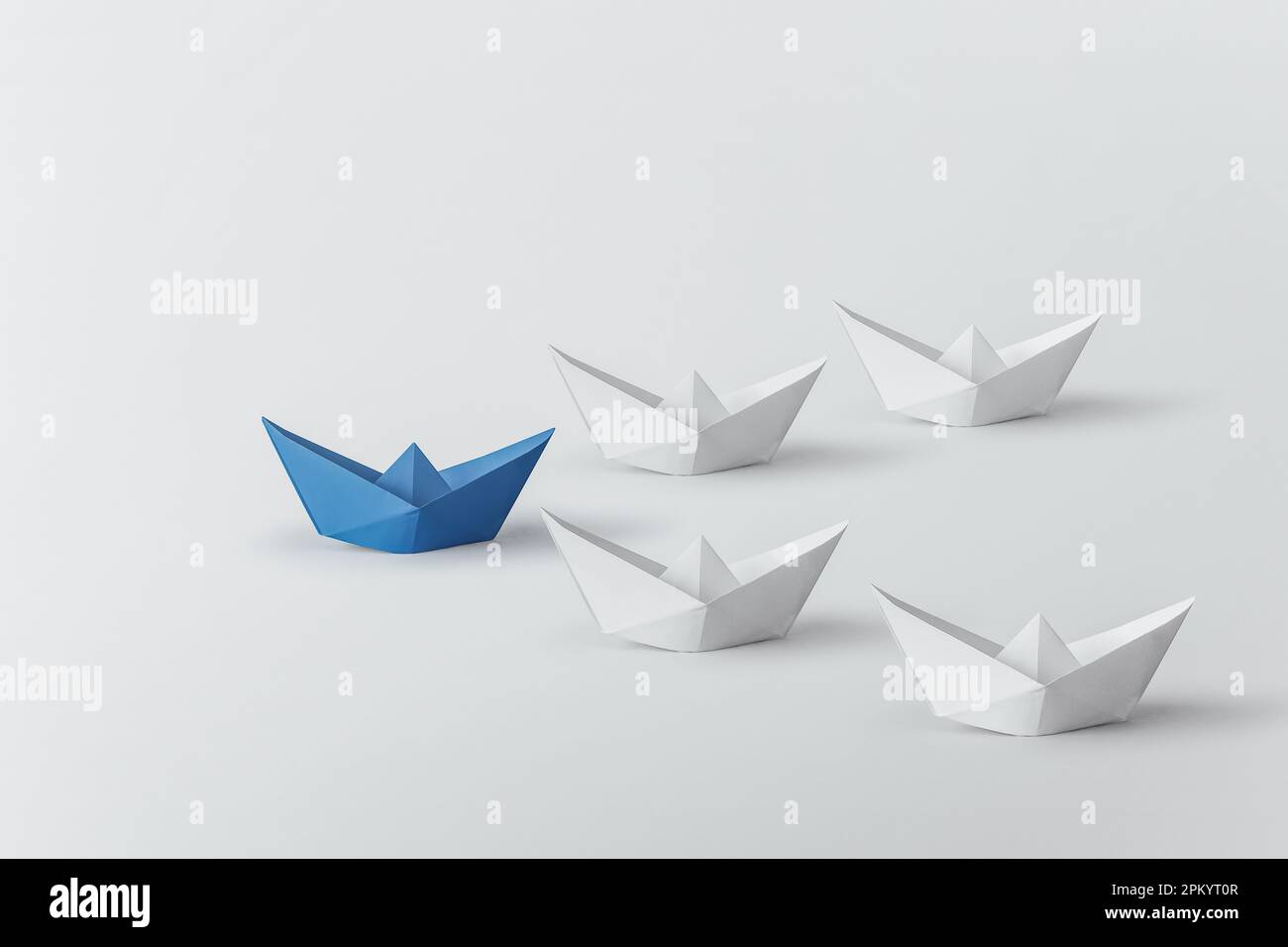 Creative image of white origami ships placed behind blue paper ship ...