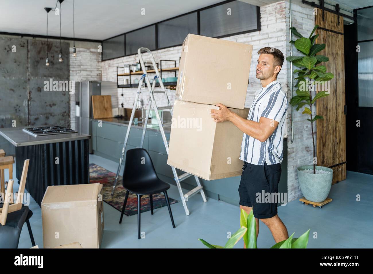 Full body side view of male in casual clothes carrying carton boxes ...