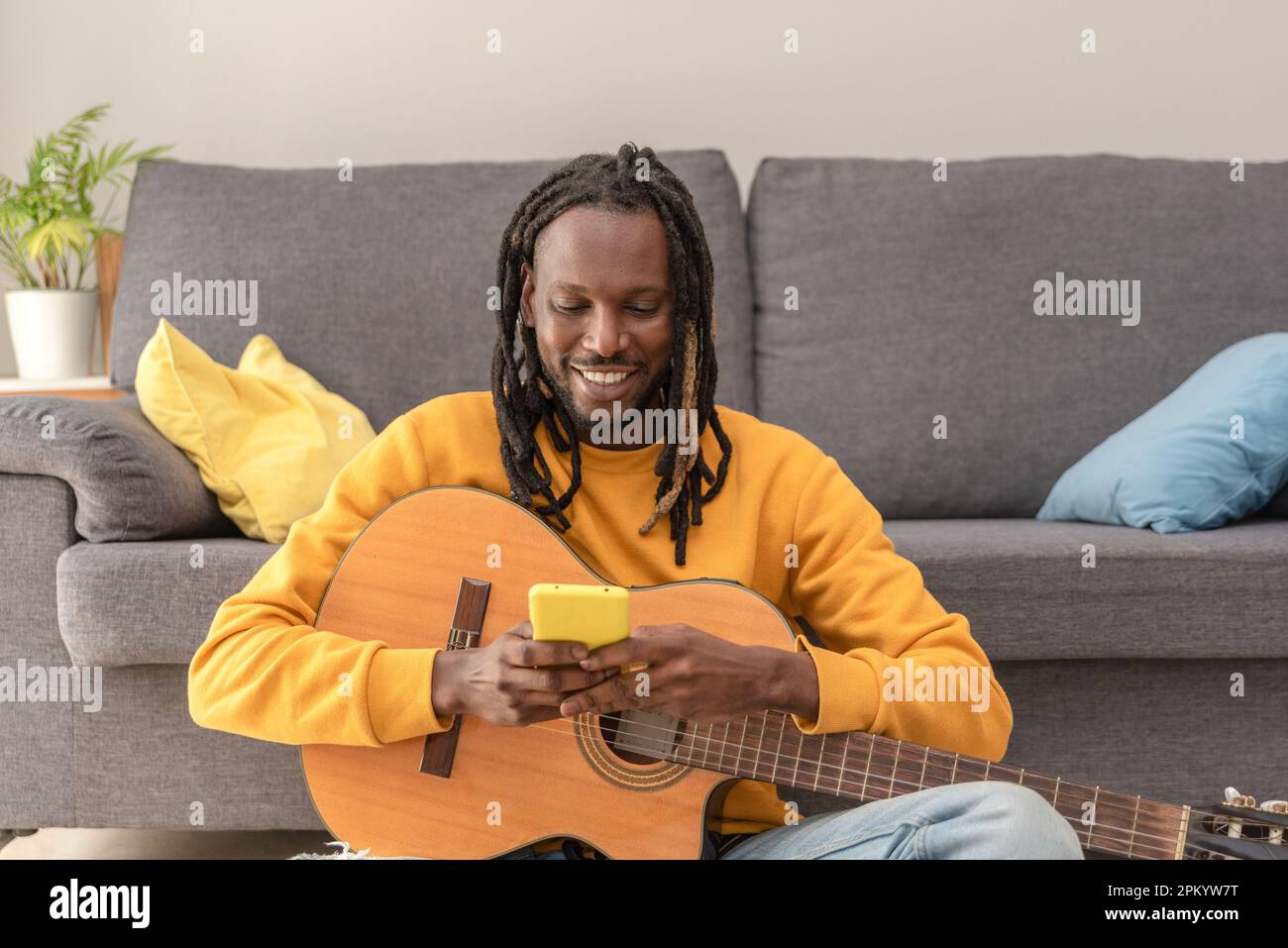 Happy African American male musician with dreadlocks sitting browsing ...