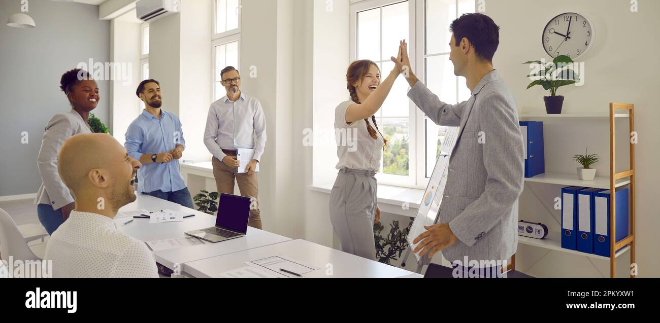 Joyful colleagues give each other high five in office after ...