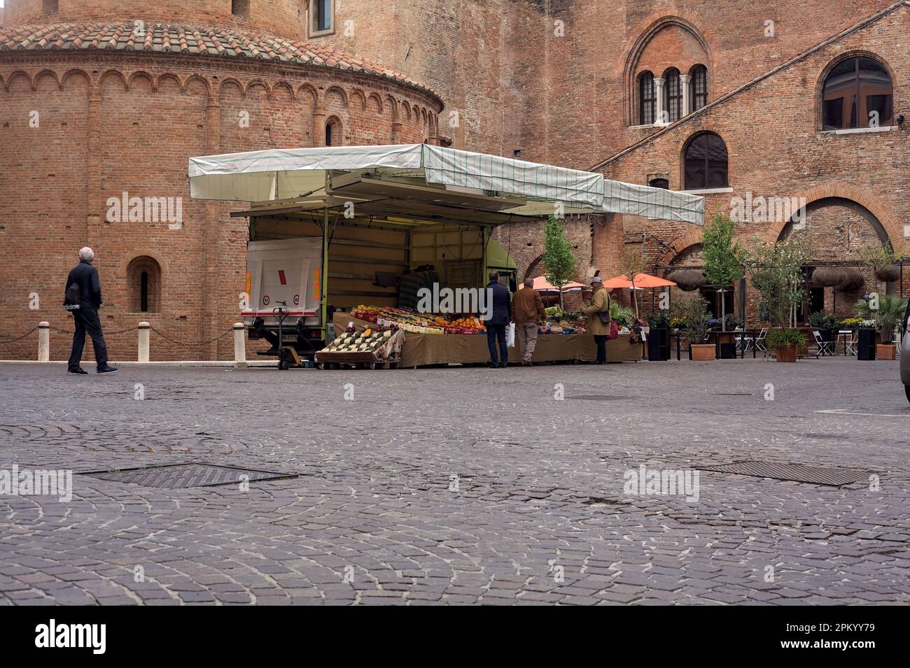 Grocery stall in a square behind historical buildings in a town on a ...