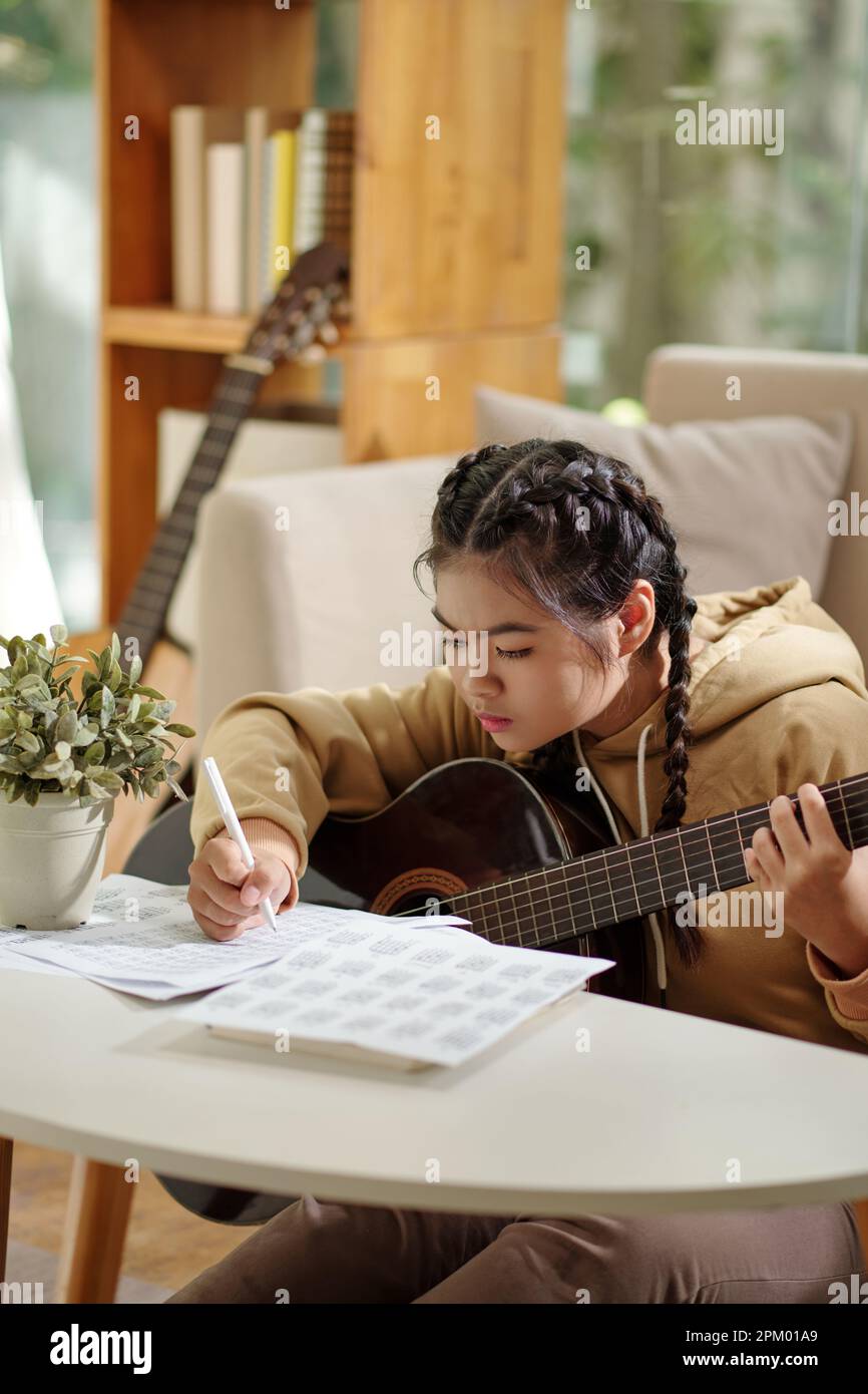 Girl plucking guitar and writing music notes Stock Photo - Alamy
