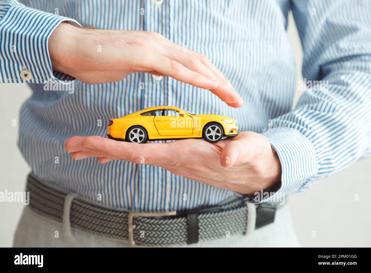 Male Insurance Agent Holding Toy Car on, Covering with Palms, Car safe ...