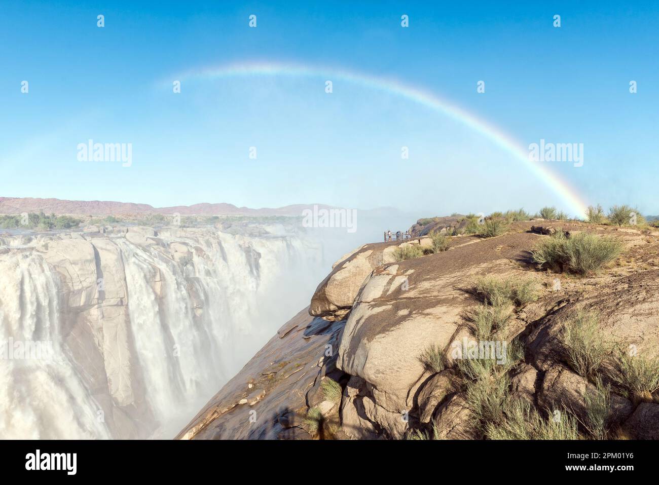 A rainbow is visible over tourists at a viewpoint at the Augrabies ...
