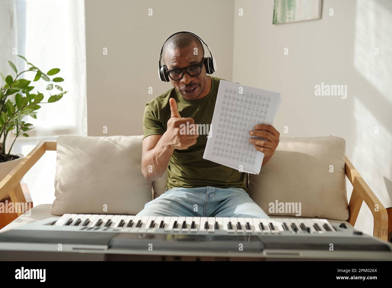 Music teacher holding music notes and showing thumbs-up Stock Photo - Alamy