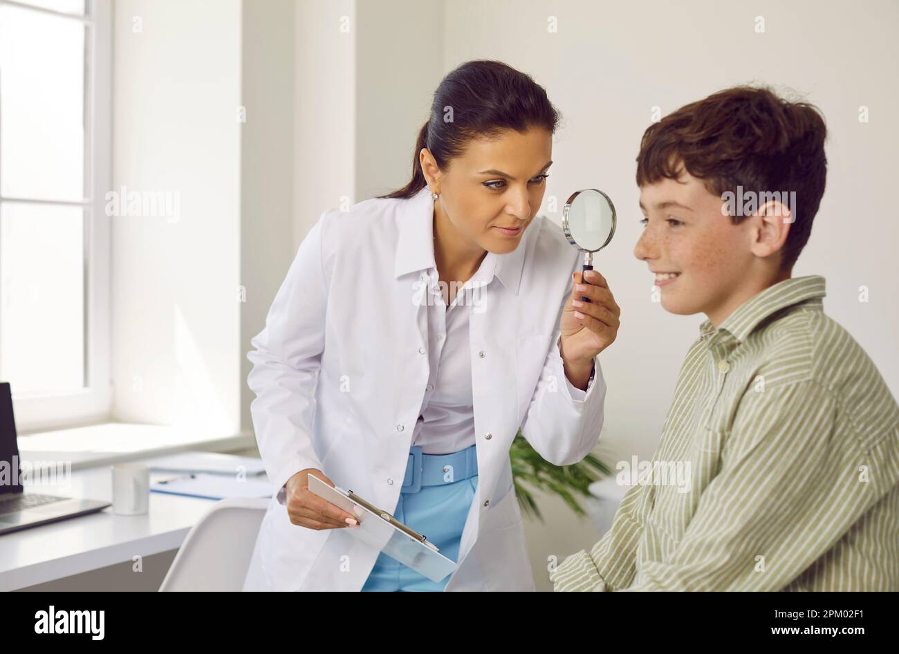Dermatologist uses magnifying glass to examine skin on face of happy ...